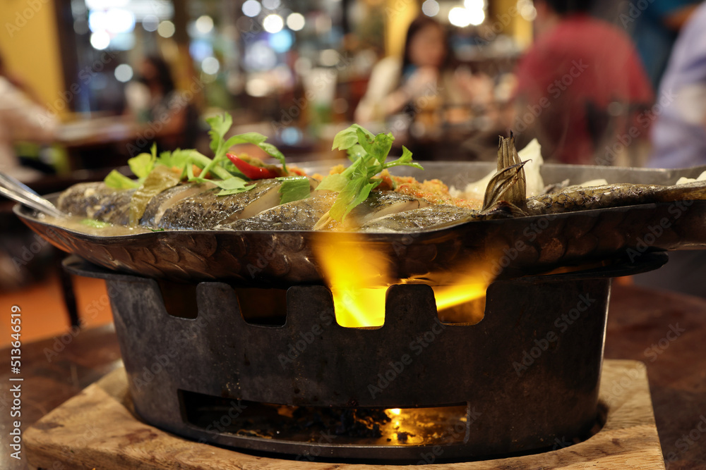 Thai style garlic lime steam sea bass barramundi fish on hot fish ...