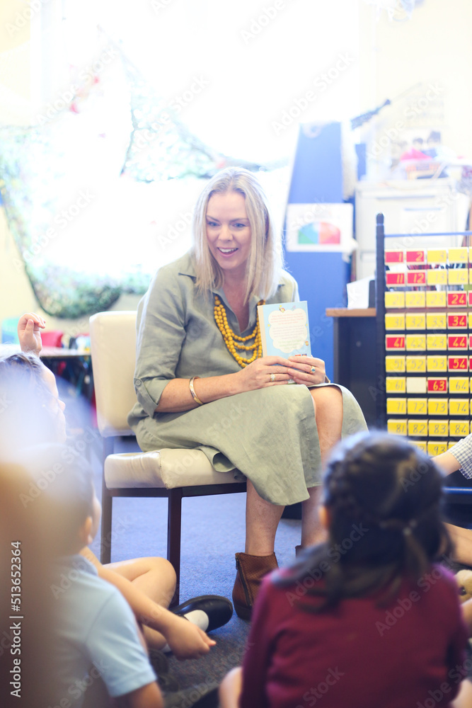 Teacher on chair, teaching children sitting on the floor Stock Photo ...