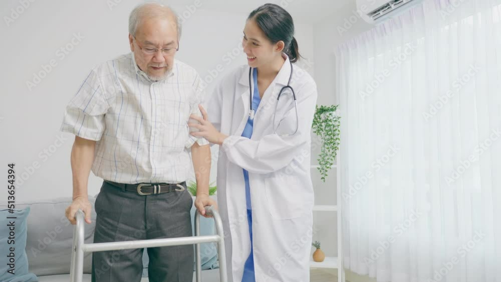 A young female doctor is helping an elderly male patient walker using a ...