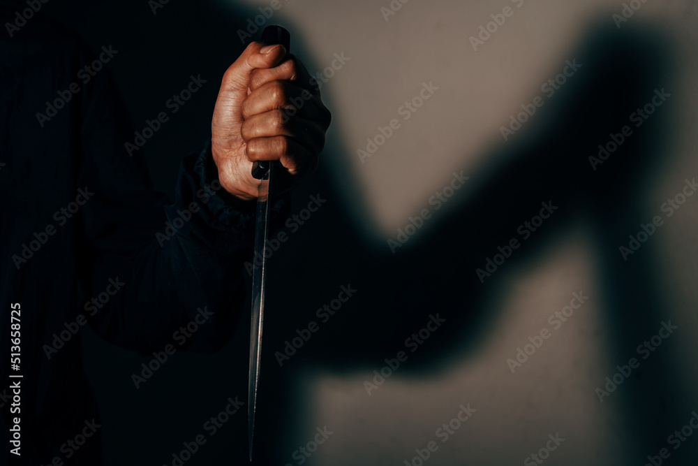 The image of a male murderer holding a knife in a dark room is ...