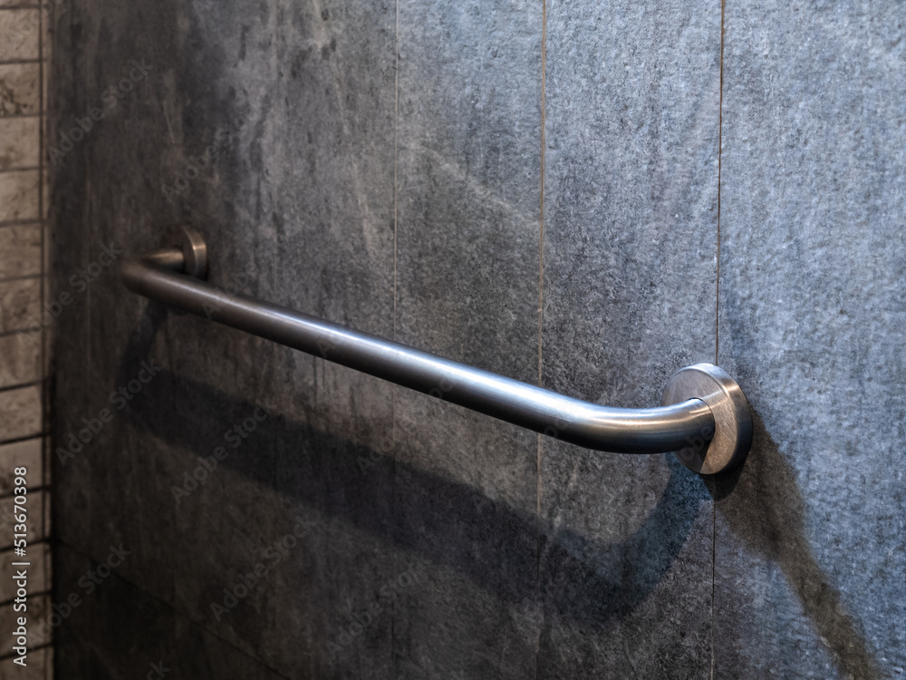 Close-up photo of stainless steel grab bar handrail installed on grey ...