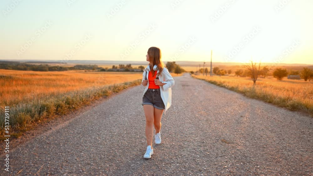 Teenage girl running across field wearing headphones and waving her ...