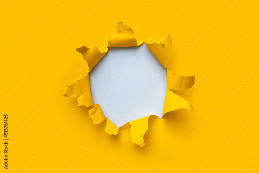 Torn hole in yellow paper with white empty background. Copy space ...
