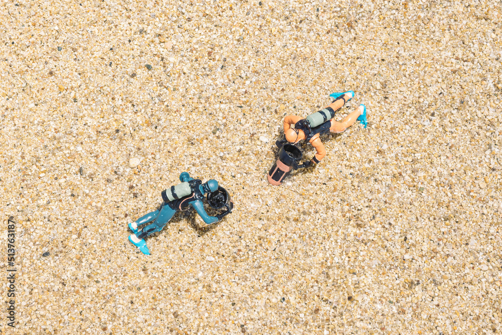 Two scuba divers drilling the sand on a sandy beach. Minimal concept ...