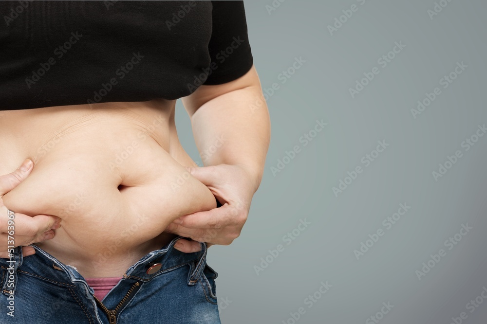 The slim girl with measure tape holds the skin on her stomach, showing ...