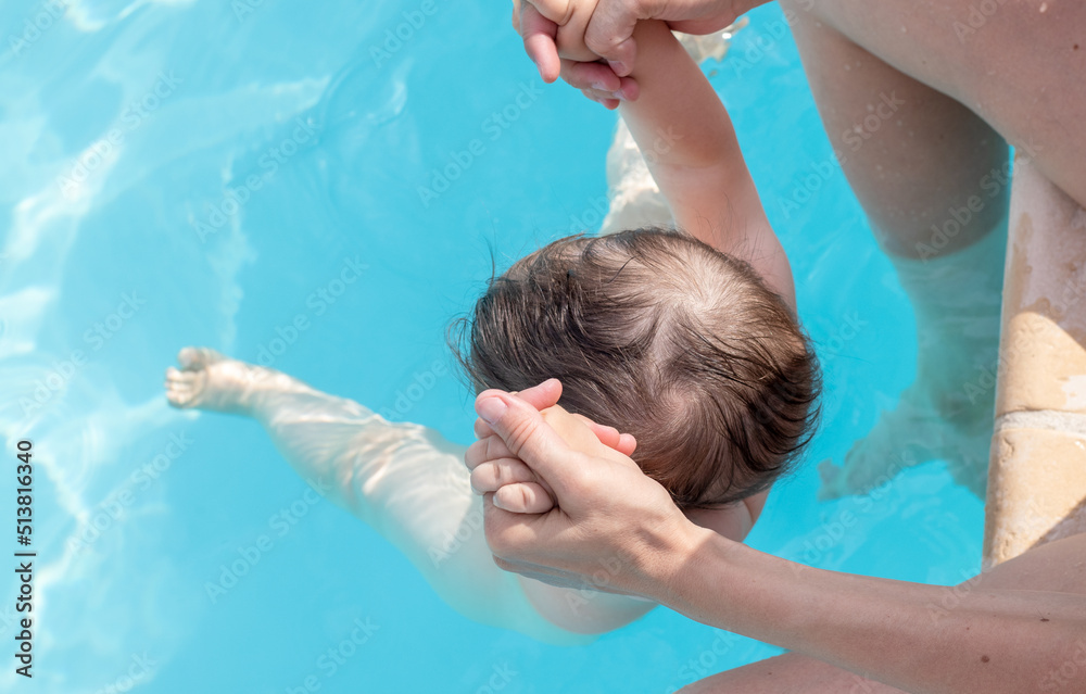mother holding little baby in pool water,top view of baby head,blue ...