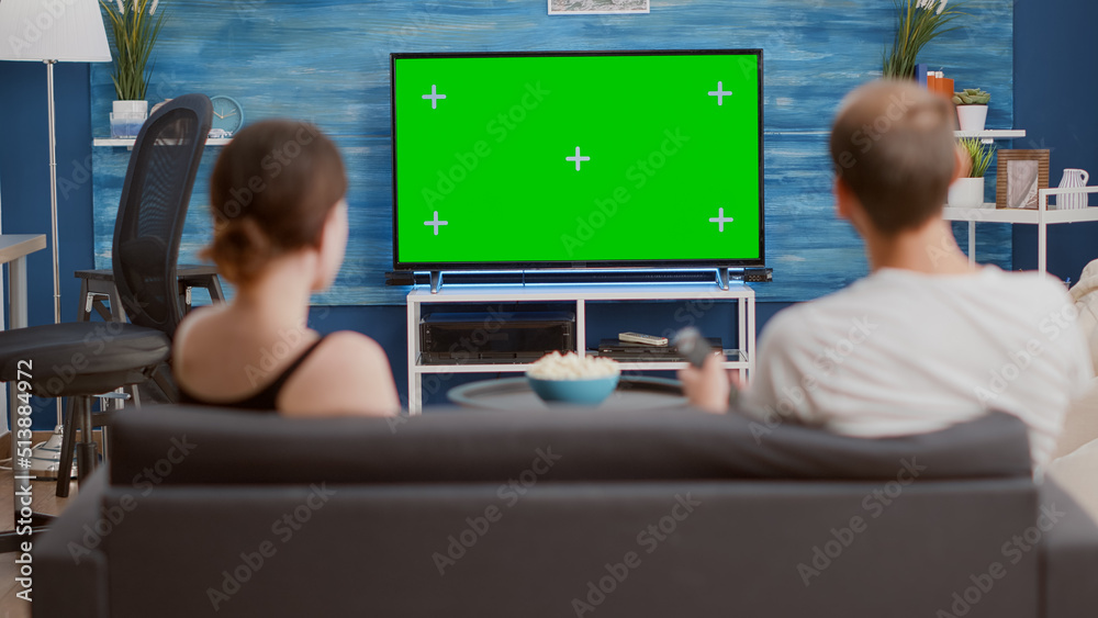 Back view of man browsing tv channels on green screen looking for ...