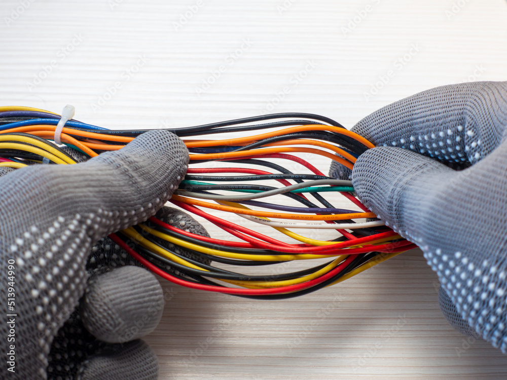 A man sorts and separates electrical colored wires with gloved hands ...