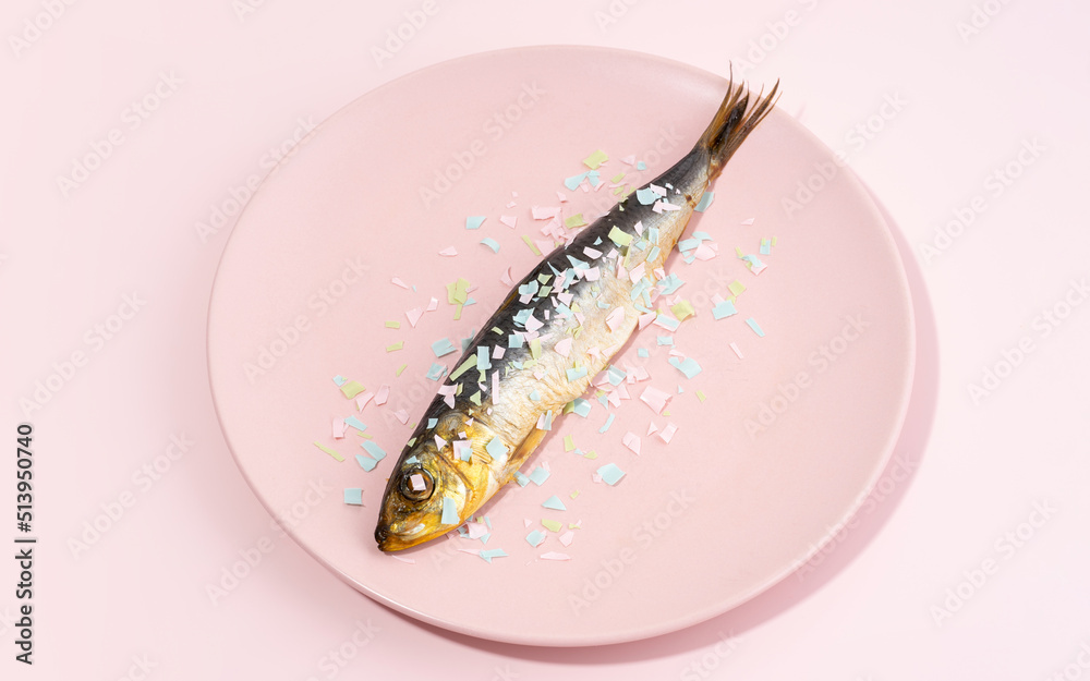 Fish covered microplastic on a pink plate. Impact of micro plastic on ...