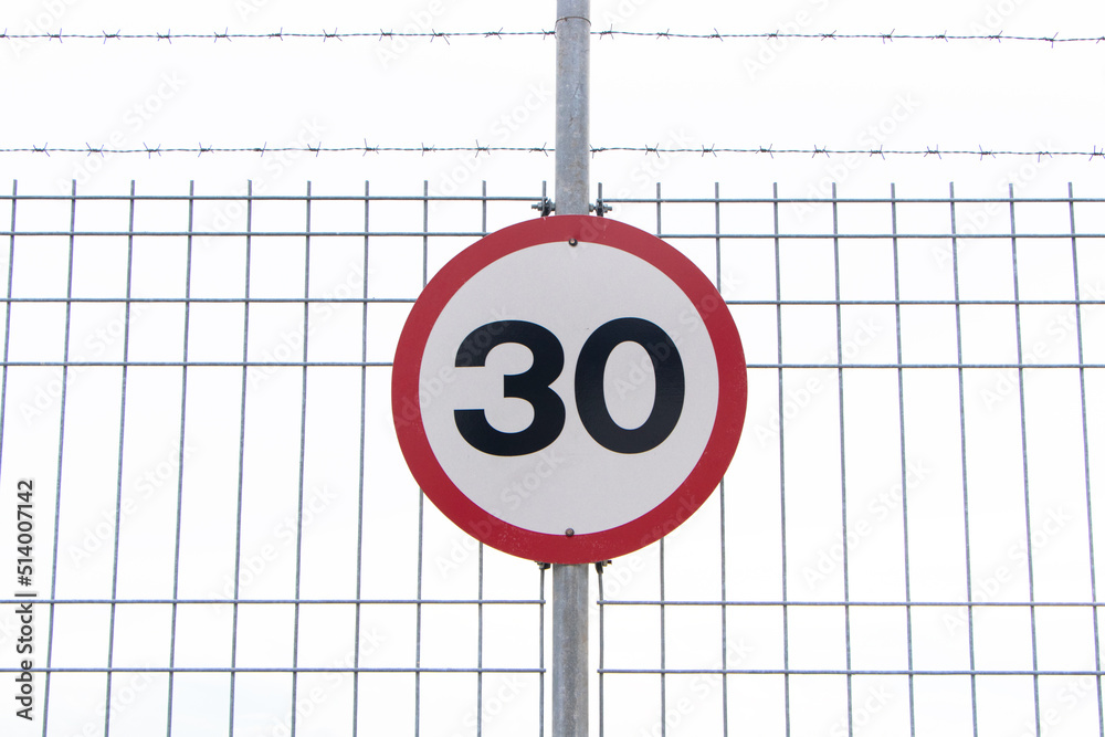 30 speed limit signs white sky background. Mounted on wire mesh fence ...