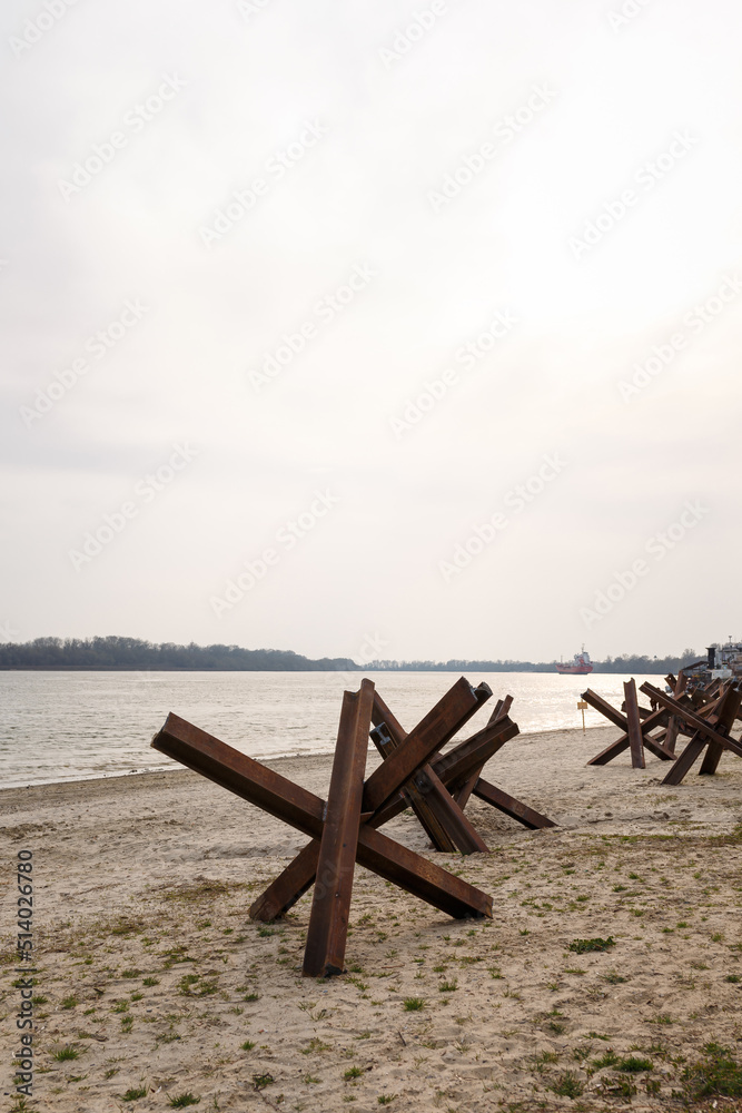 Military anti-tank czech hedgehogs on river bank. Metallic barricade or ...