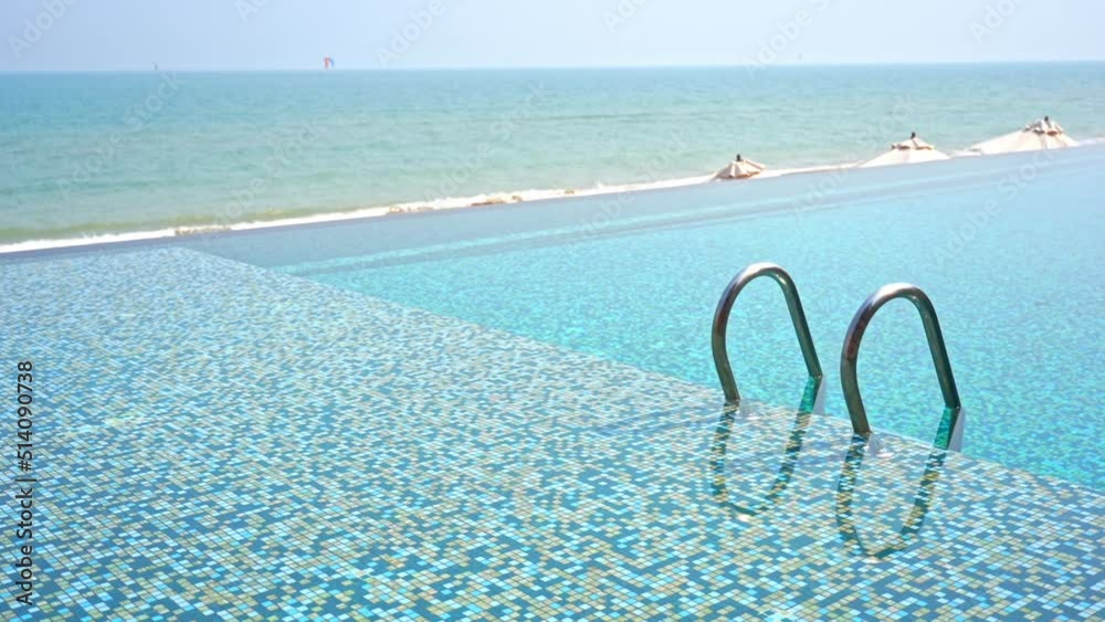 Empty seafront infinity pool entrance with metal handrails. The edge of ...
