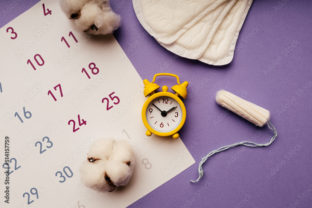 Alarm clock on calendar with menstrual sanitary pads and tampon. Women ...