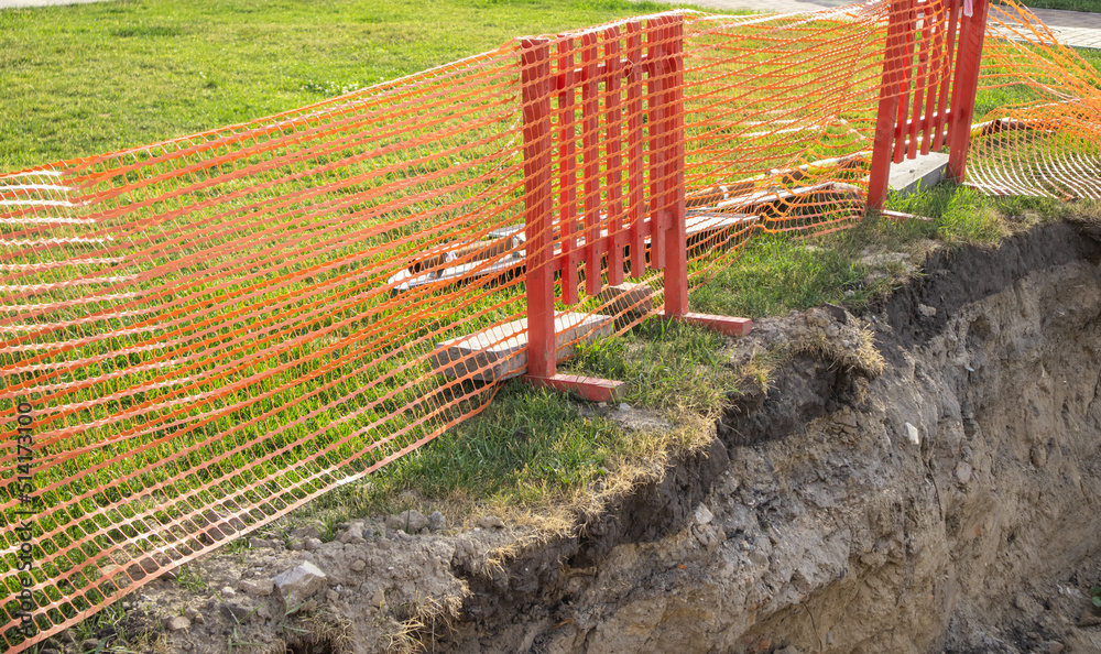 Protective fencing on the edge of the trench during the repair work of ...