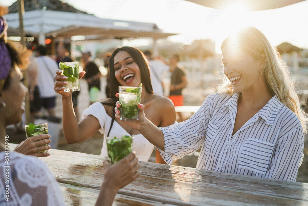 Happy girls having fun cheering with cocktails at bar on the beach ...