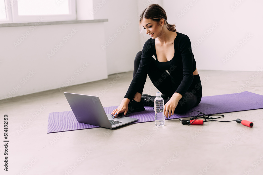 Fitness lifestyle. Woman is watching at a laptop video tutorial of ...