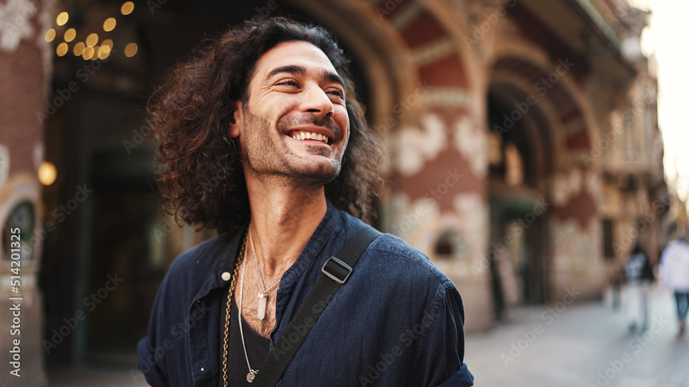 Young italian guy with long curly hair and stubble looks around looking ...