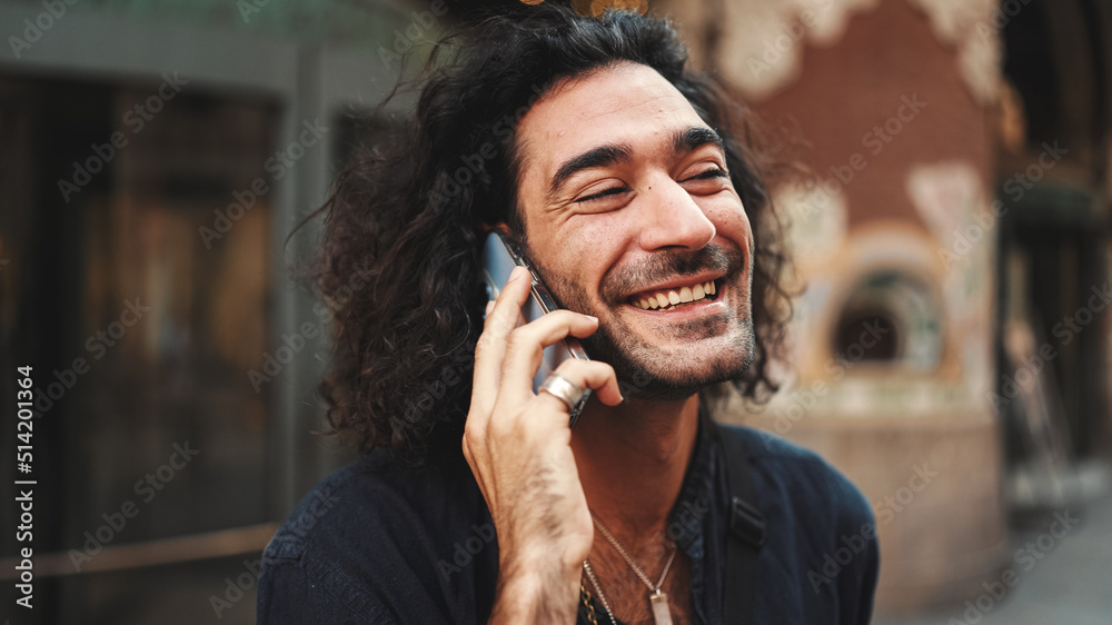Young attractive italian guy with long curly hair and stubble is using ...
