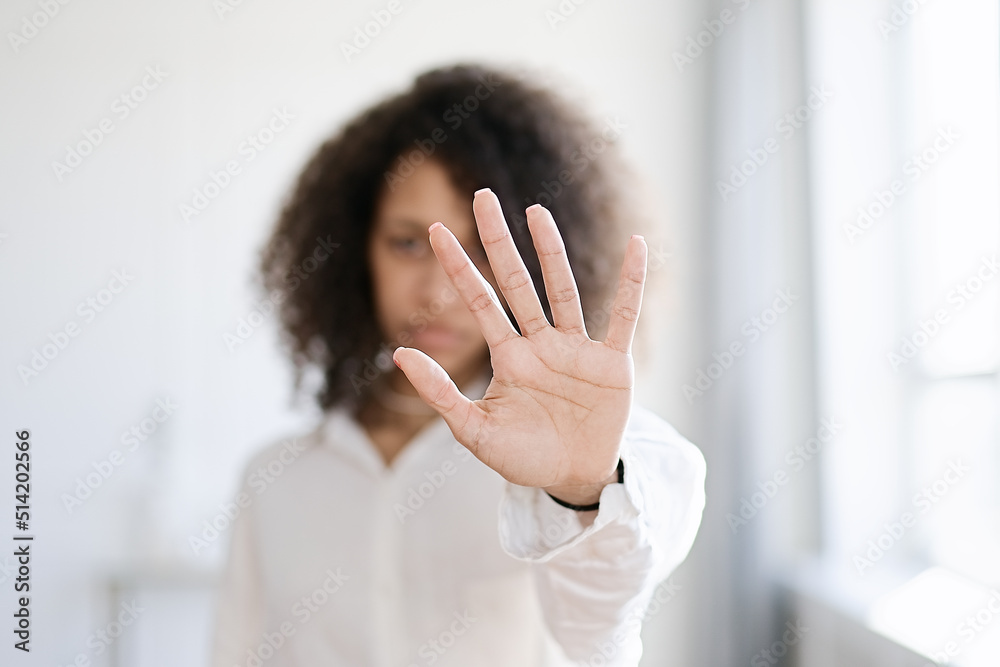 Portrait of serious African American young woman holding hand in stop ...