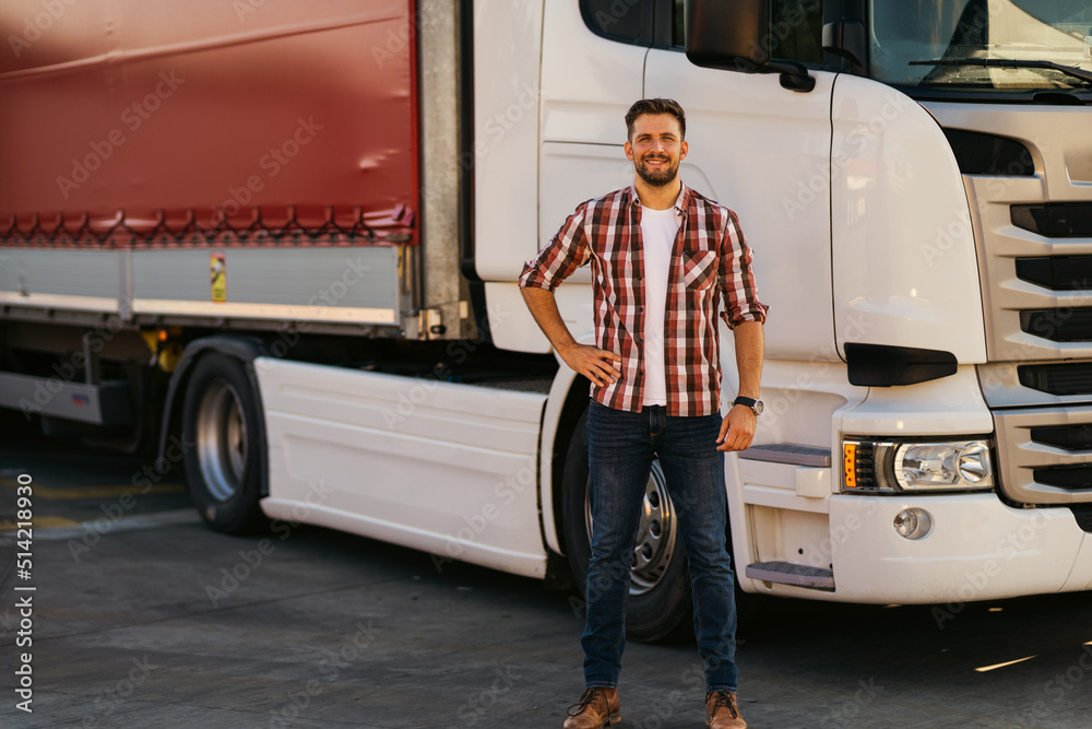 smiling handsome masculine driver stranding next to his white truck ...