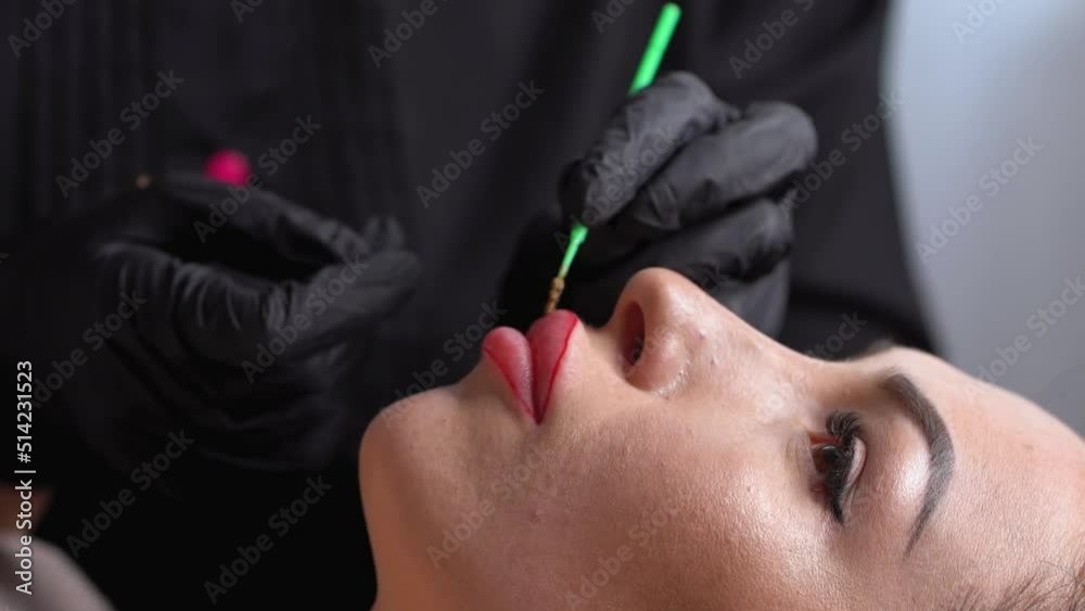 close-up, female lips. Hand, in medical glove, applies soothing lip ...