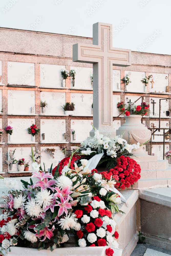 tomb with Christian cross and flowers in a cemetery. Niches and tombs ...