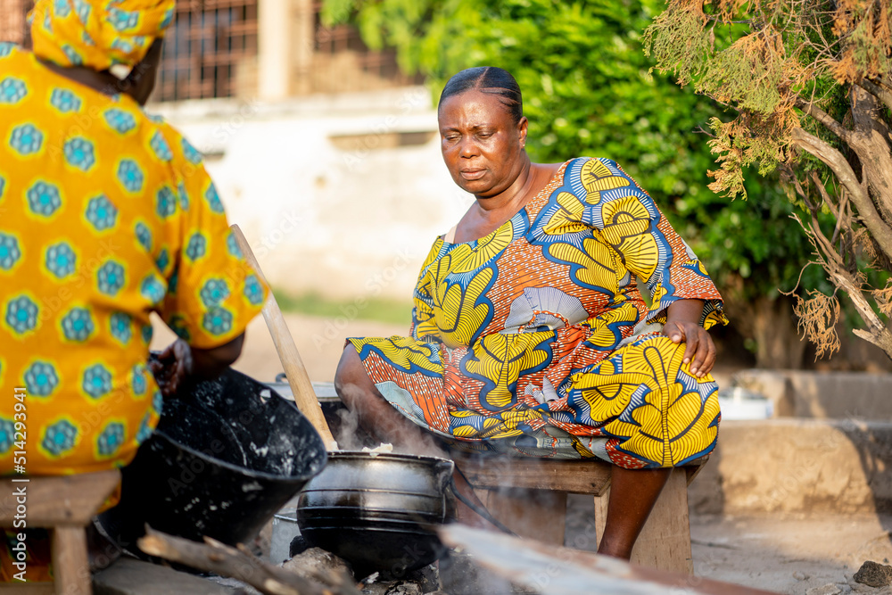 candid image of african women cooking out door- seated black women in ...
