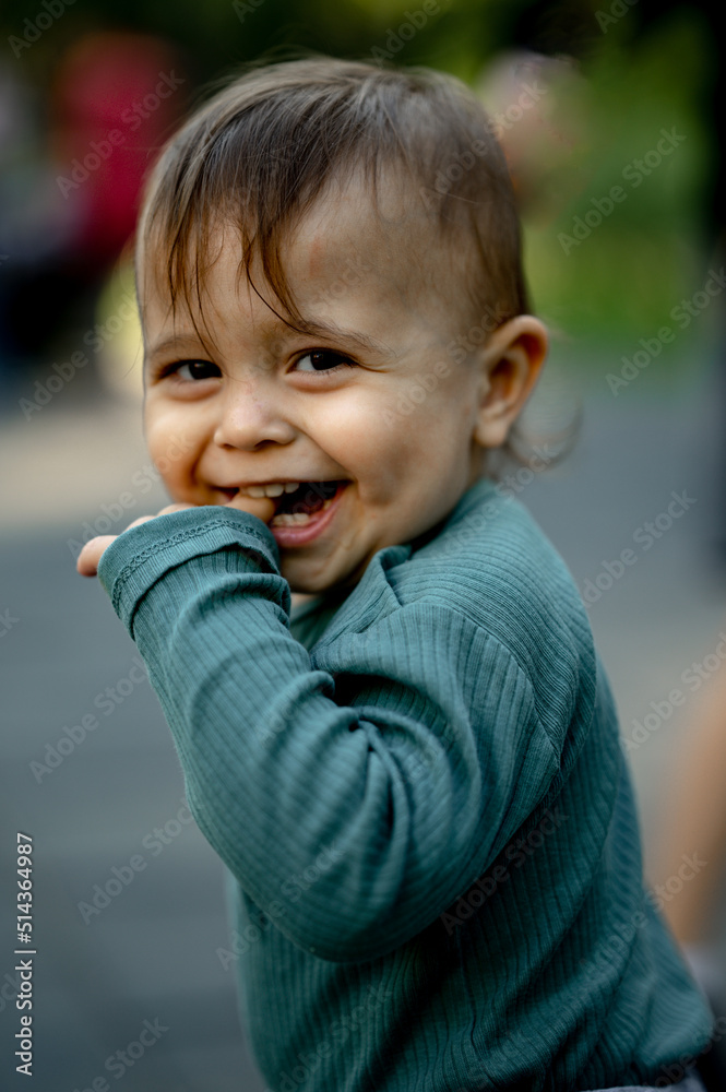 portrait of a one-year-old boy in a green blouse. The kid is standing ...