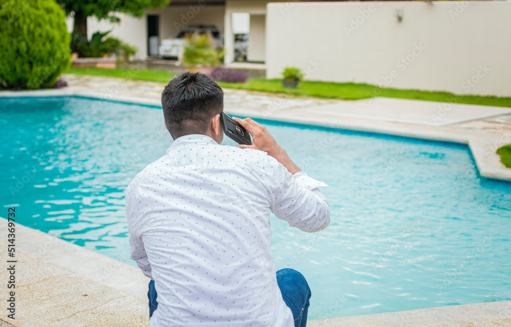 Handsome man sitting calling on the phone near the swimming pool, Young ...