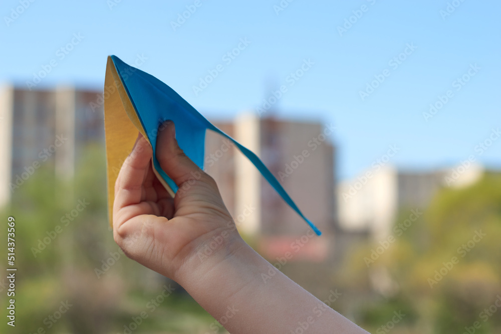 Hand holding the paper flag painted in colors of Ukrainian yellow-blue ...