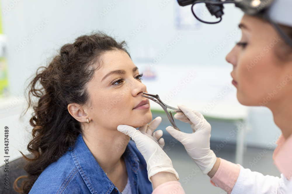 Doctor otorhinolaryngologist checking nose with otoscope of patient at ...