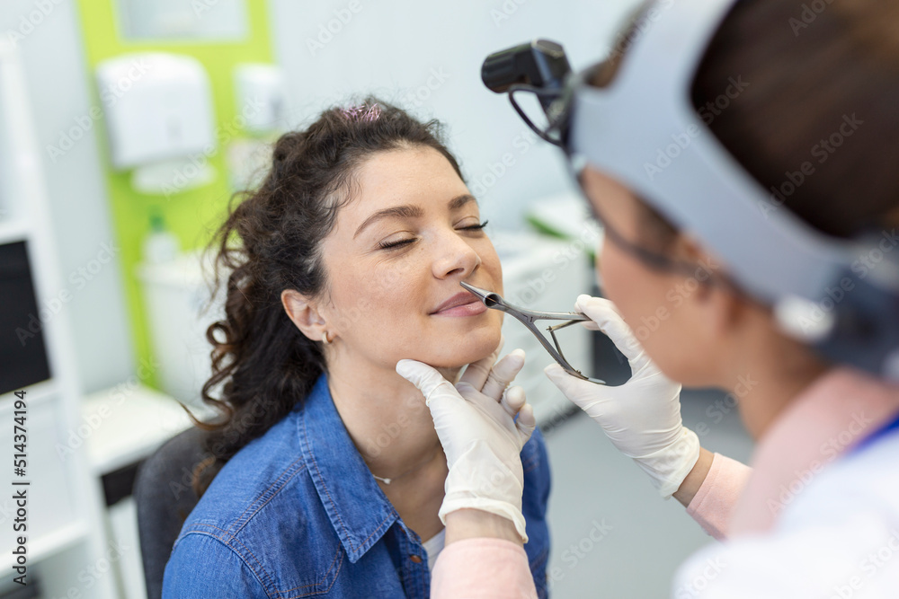 Doctor otorhinolaryngologist checking nose with otoscope of patient at ...