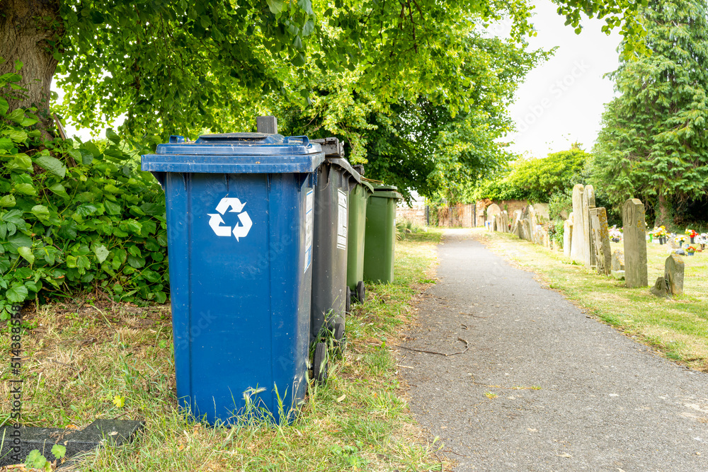 Plastic recycling and green waste bins seen by a path in a rural ...