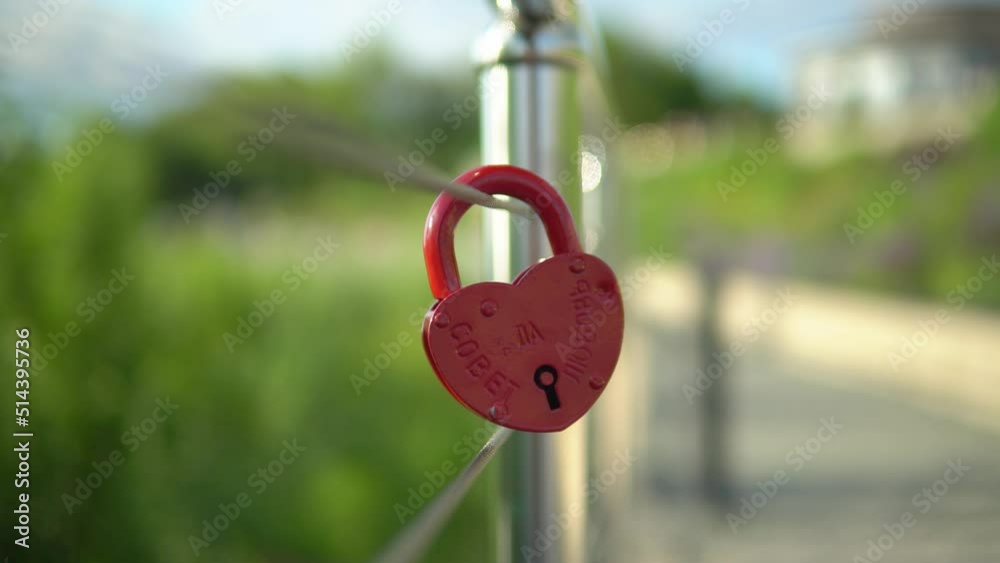 On the railing hangs a wedding lock of red in the form of a heart. A ...