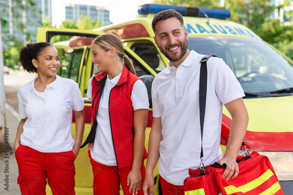 Multi-ethnic paramedics standing at the fromt of an ambulance ...