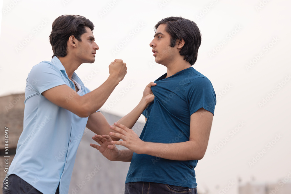 One teenage boy pulling the other by the collar of his shirt against ...
