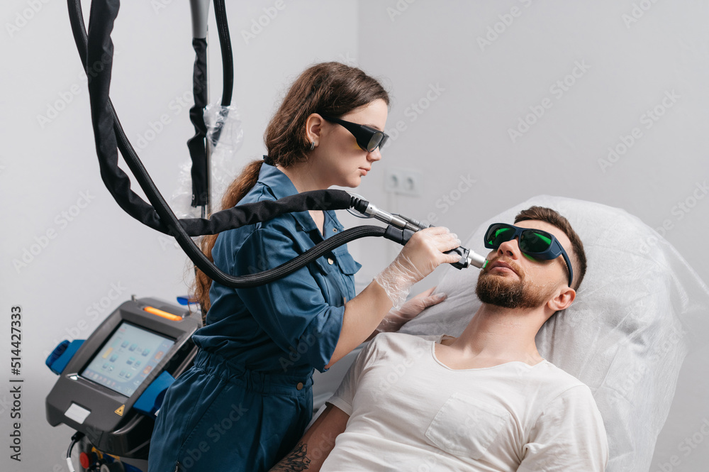 Laser depilation of beard contour. The depilation master treats the ...