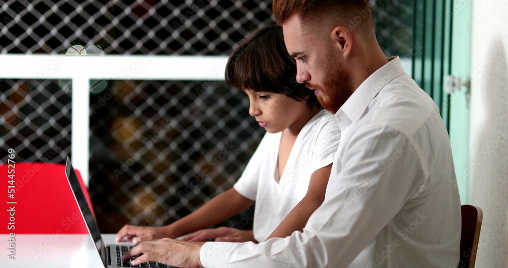Candid parent and child together in front of computer doing homework at ...