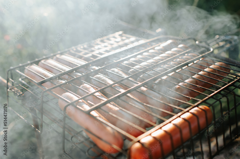 Cooking fried food on fire with smoke in nature. Close-up of sausages ...