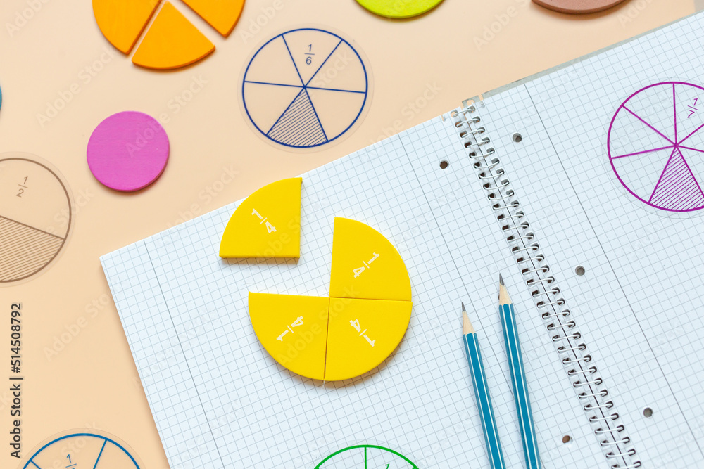 Open notepad, fractions, chart, pencils on a beige background. Close up ...