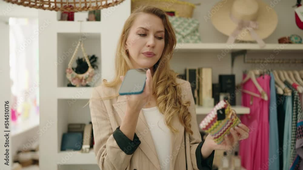 Young blonde woman shop assistant talking on the smartphone holding ...