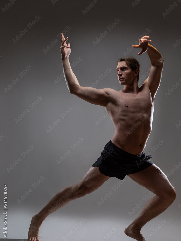 Muscular man in an artistic pose, portrait on a gray background. An ...
