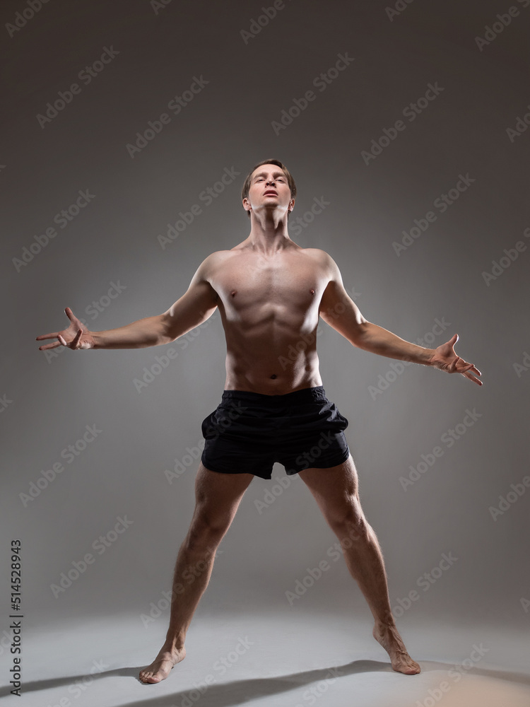 Muscular man in an artistic pose, portrait on a gray background. The ...