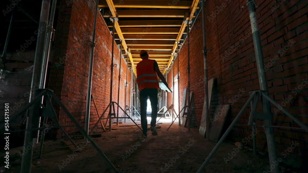 Builder inside the house. The builder goes inside the building under ...