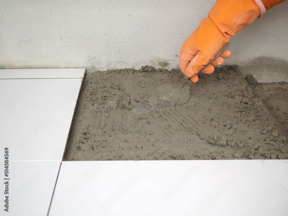 Laying floor ceramic tile. construction workers laying tile over ...