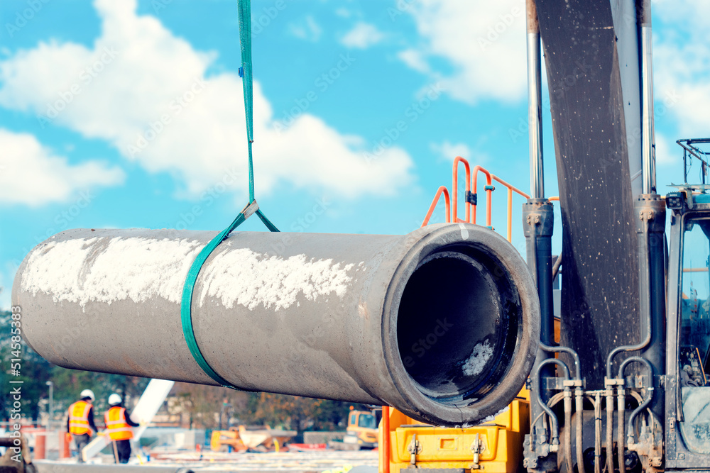 Concrete drainage pipe lifted by excavator during deep drainage works ...