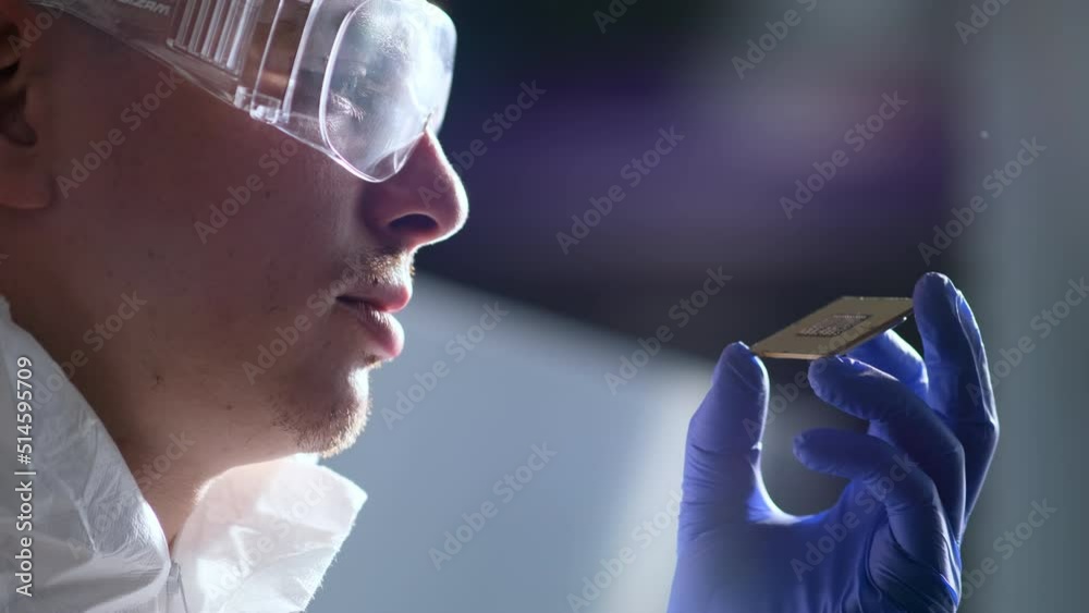 A young computer engineer holds and tests a processor. Close-up of a ...