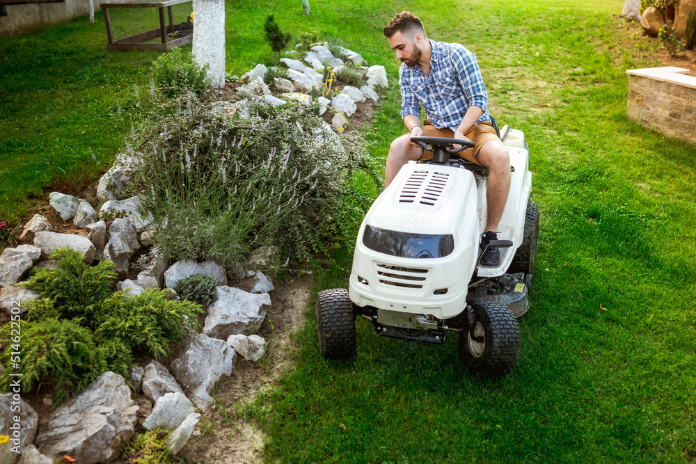 professional gardener doing landscaping works - driving and cutting ...