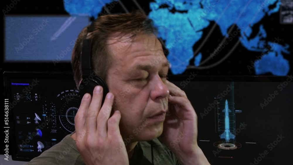 An elderly military man with headphones looks at the monitor against ...