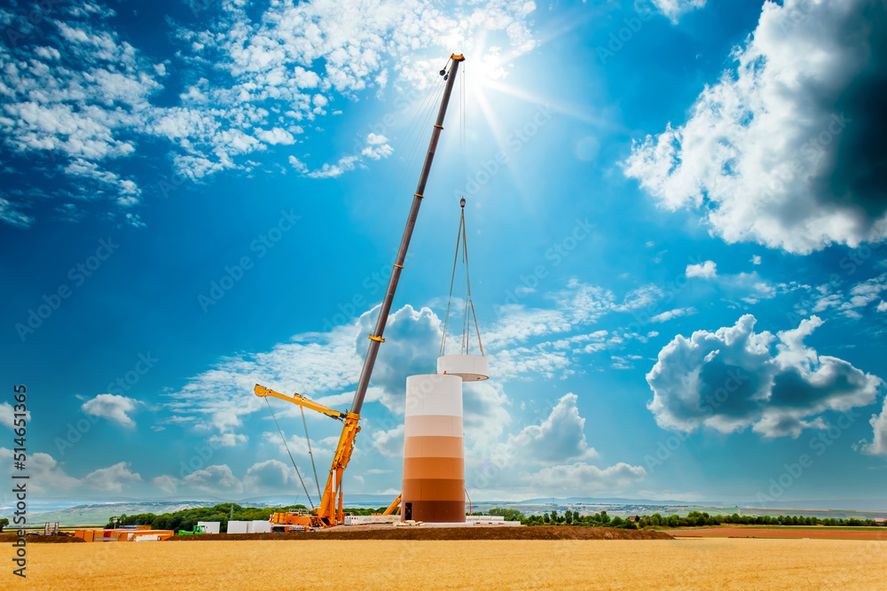 Building and assembling a construction windmill by crane. Farmland with ...